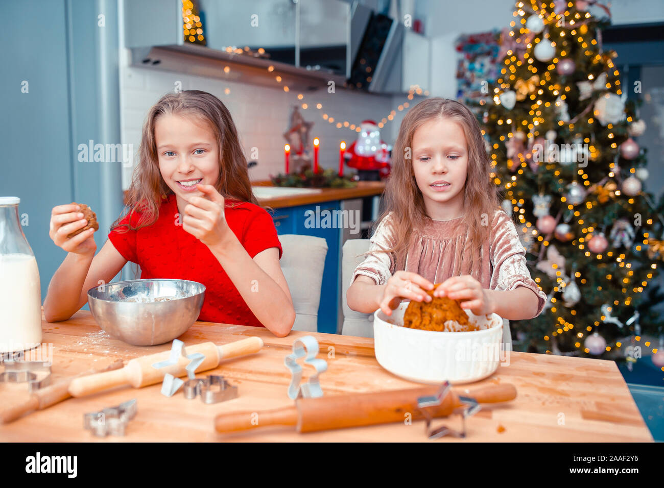 Adorable little girls baking cookies background of lights and Christmas ...