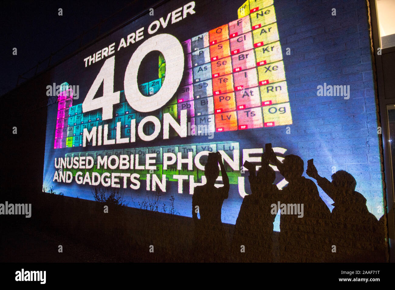 Students hold up mobile phones against a light display at the ...