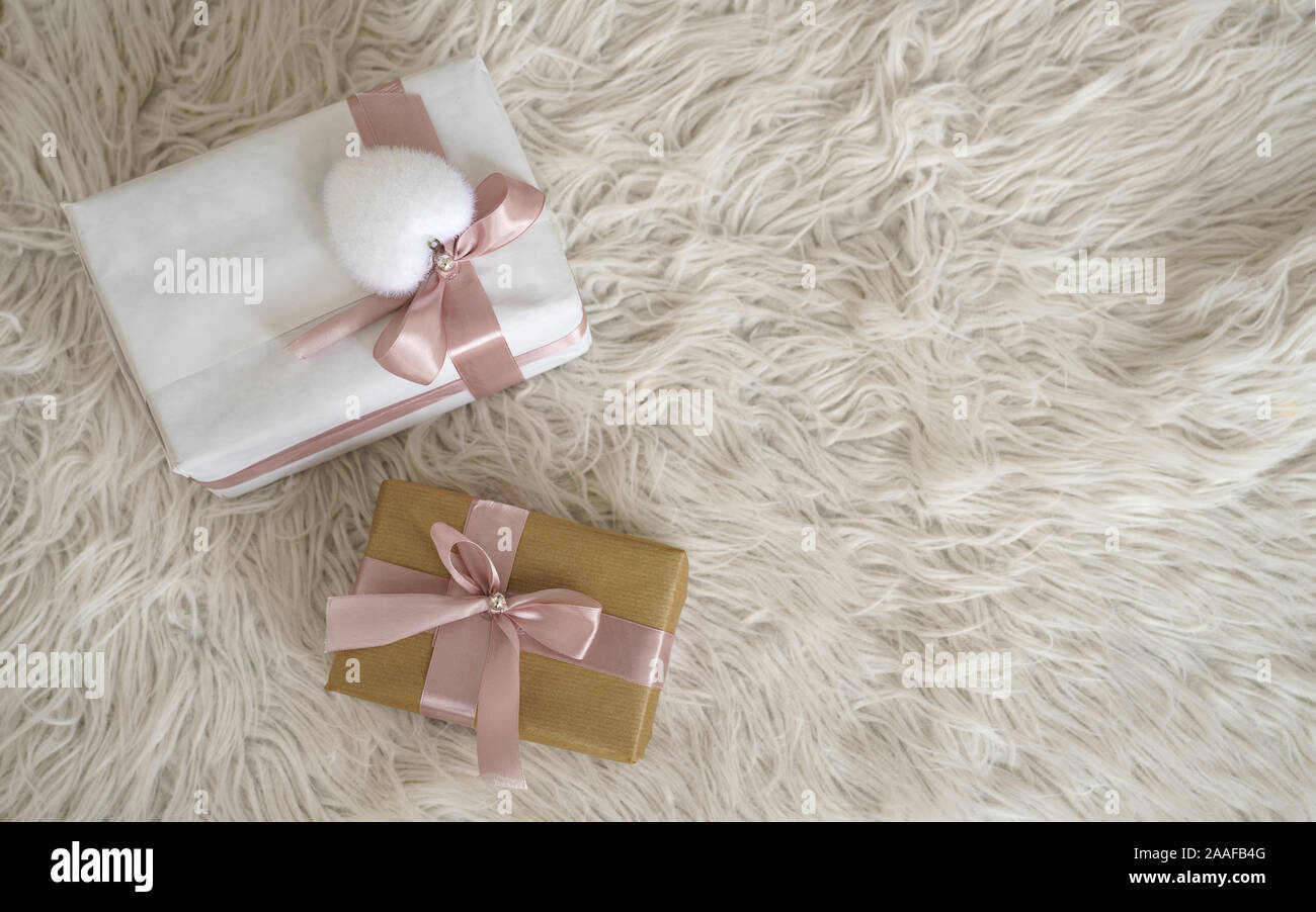 Top view White and brown gift boxes with pink ribbon on white fluffy ...