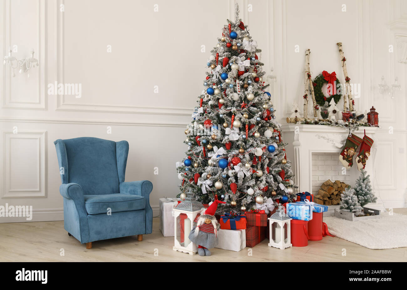 Blue armchair and gift boxes under decorated Christmas tree beside the ...