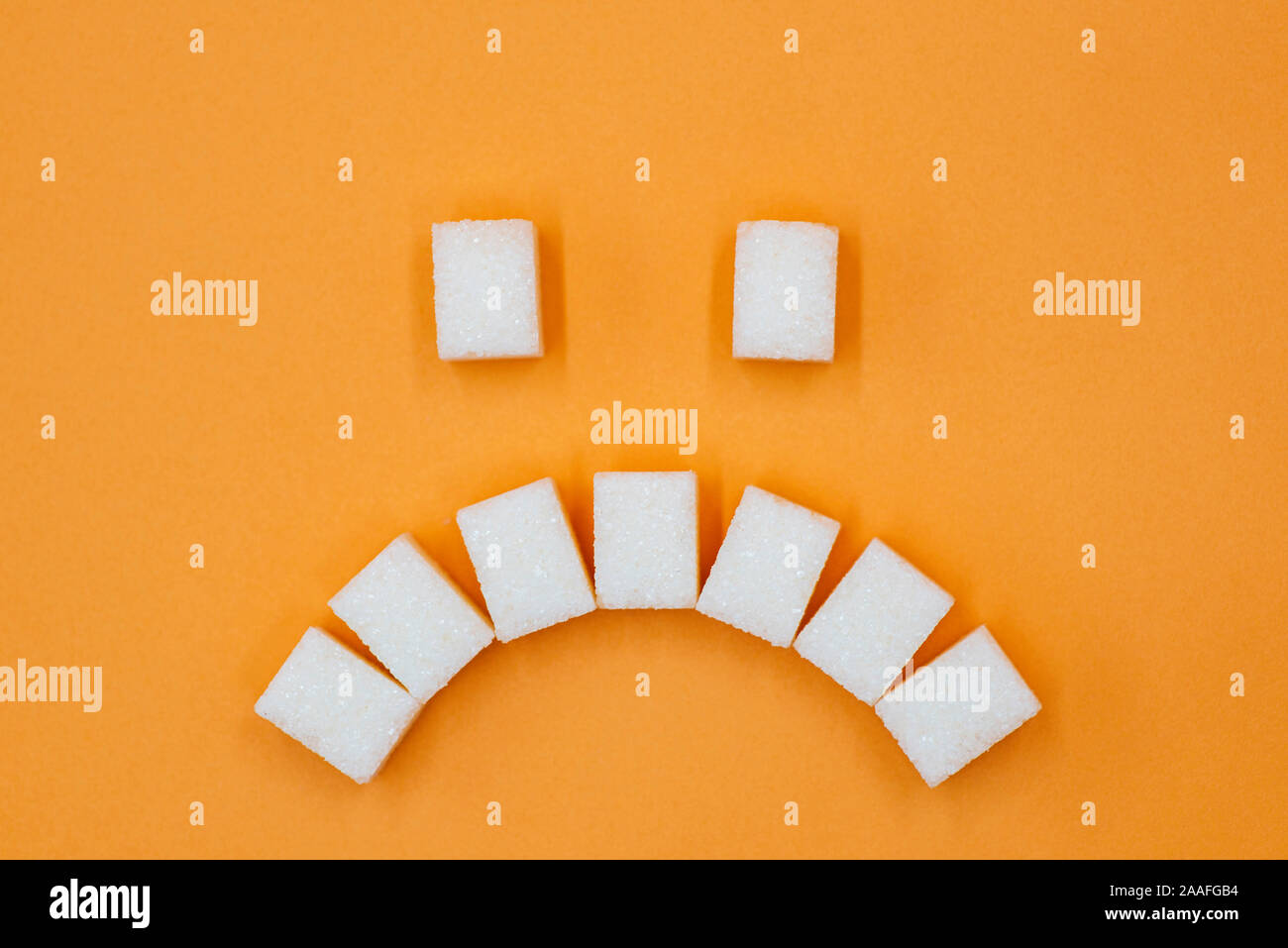 Sad face symbol, composed of cubes of sugar. Concept of sugar leading ...