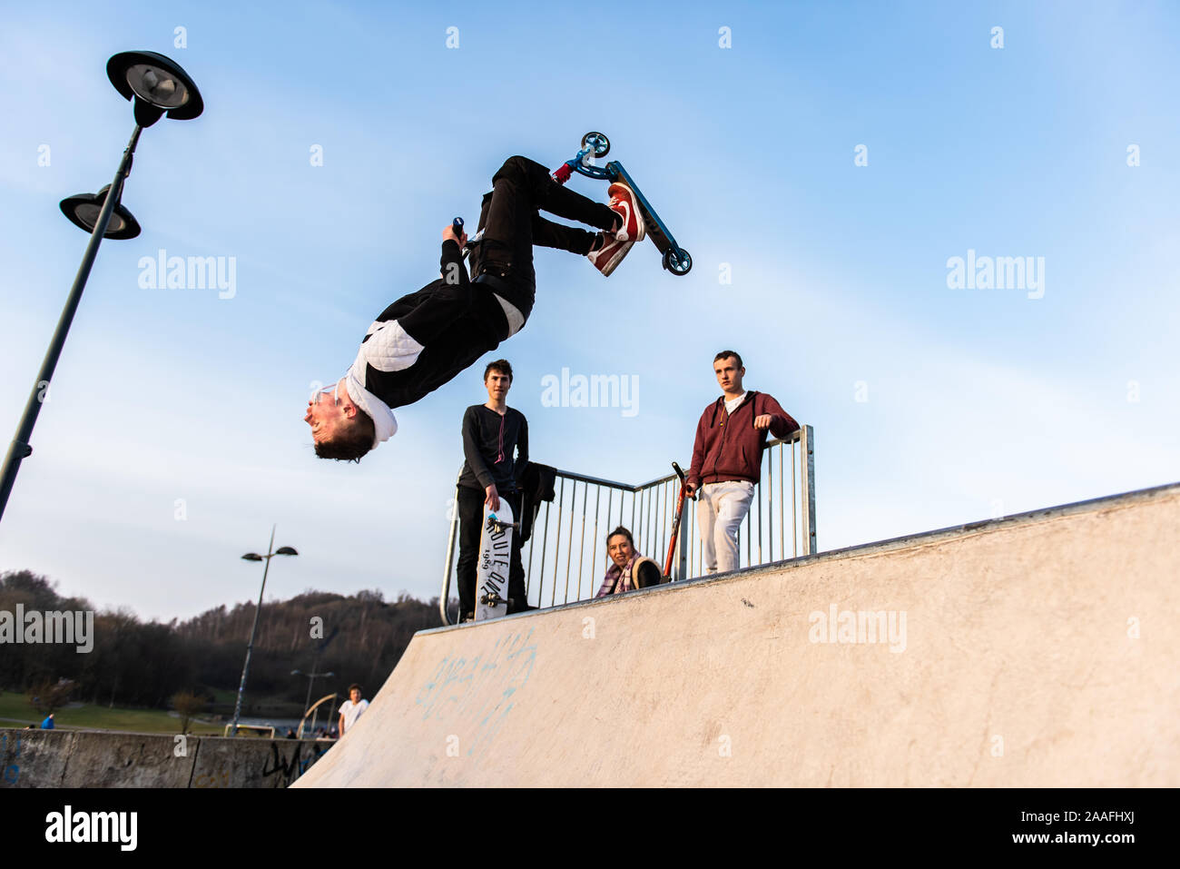 A young teenage boy does a somersault on a concrete skate ramp without ...