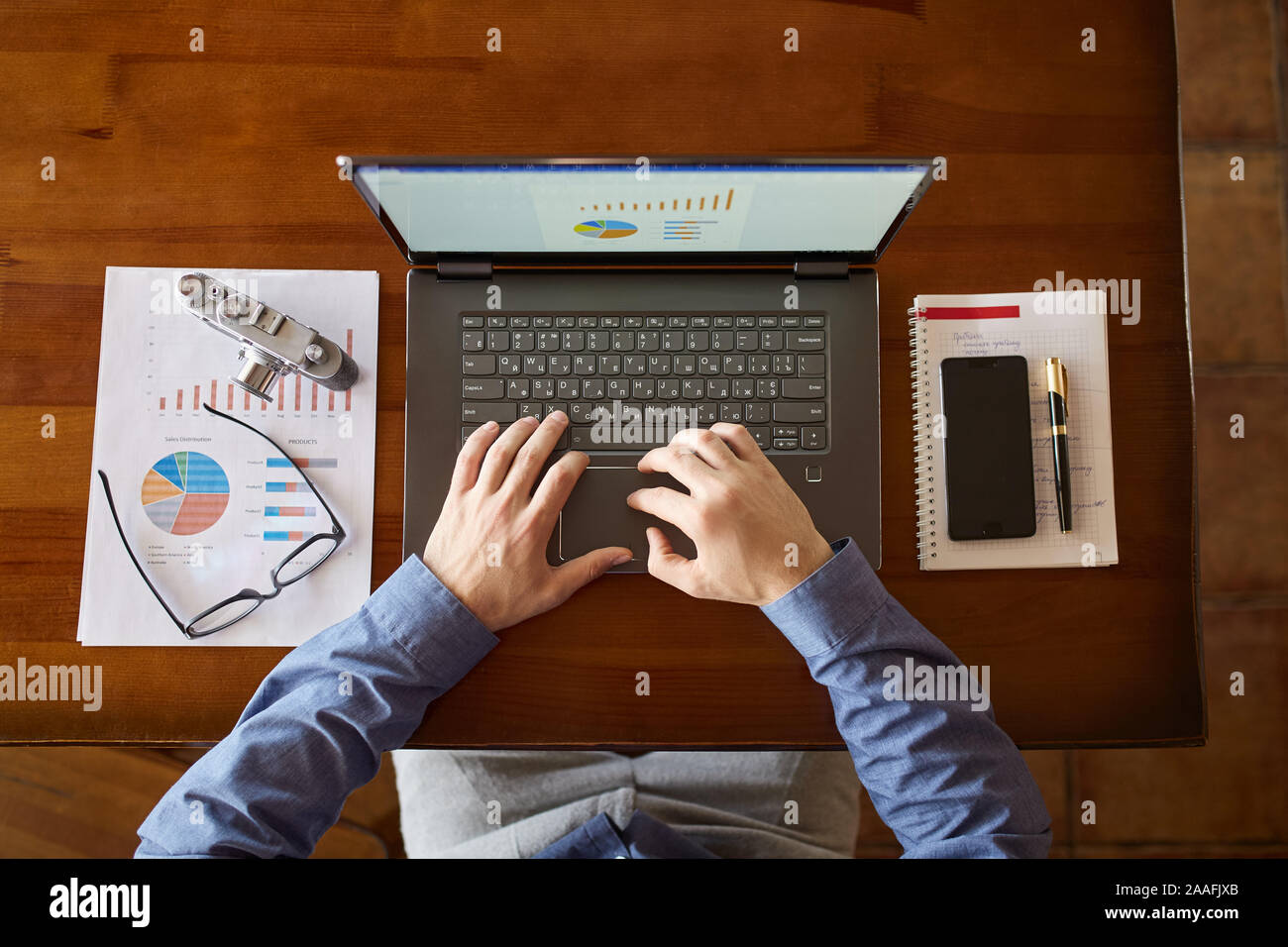 Top view of hipster vintage wooden desktop workplace. Male hands typing ...