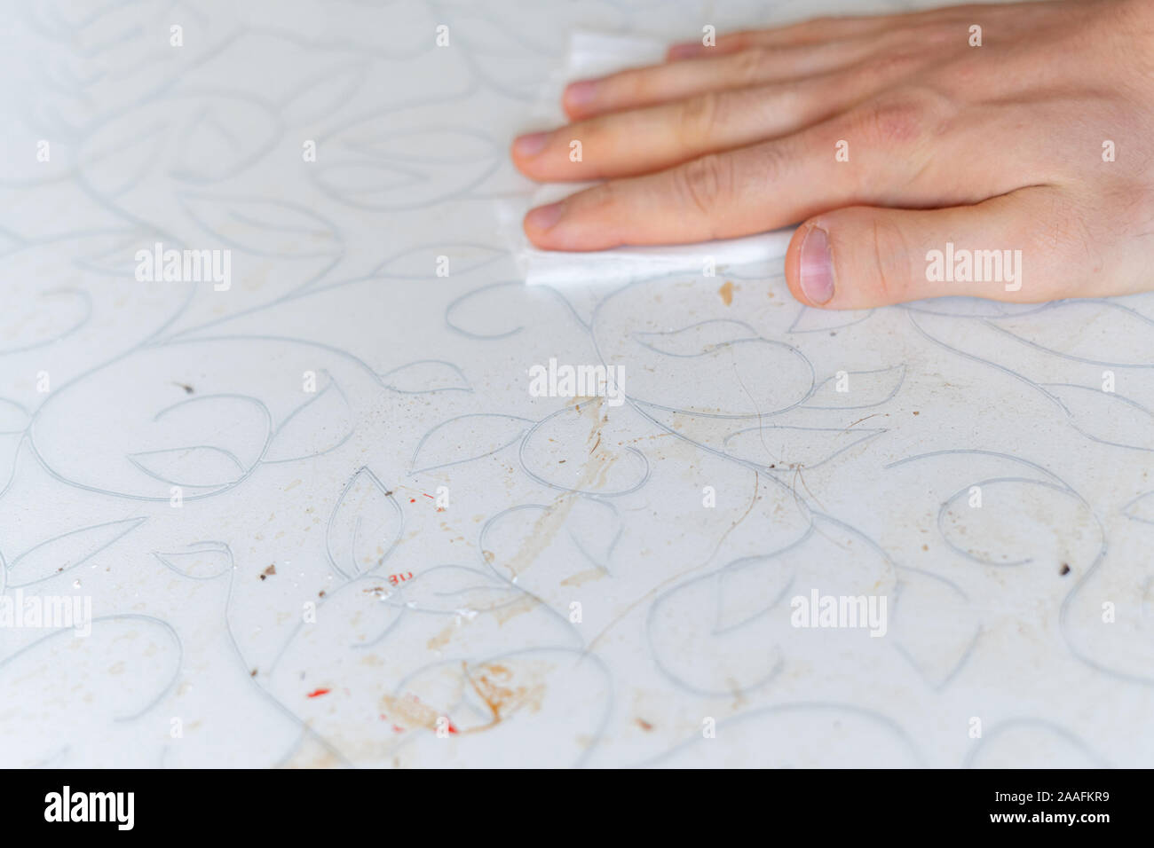 hand with a white rag wiping the dirty table surface in kitchen at home ...