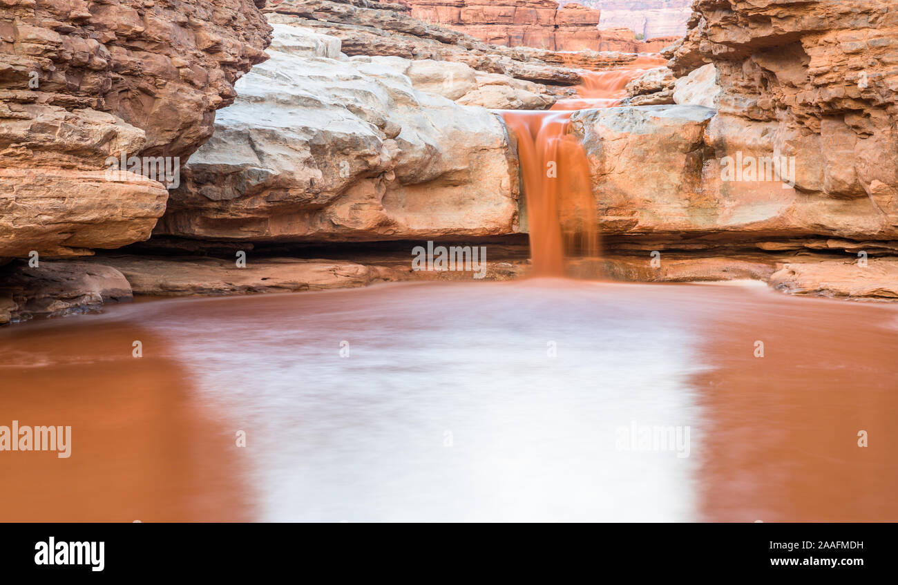 Waterfall during flash flood in Moab Utah. A large pool of red water ...