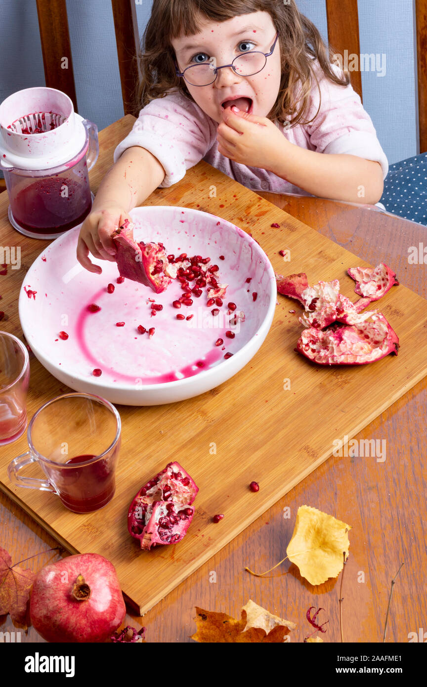 Young girl squeezing pomegranate juice, eating seeds, making a mess on ...