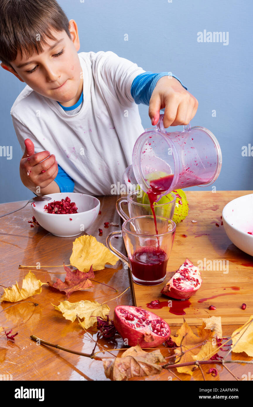Young boy squeezing and pouring pomegranate juice, making a mess. Face ...
