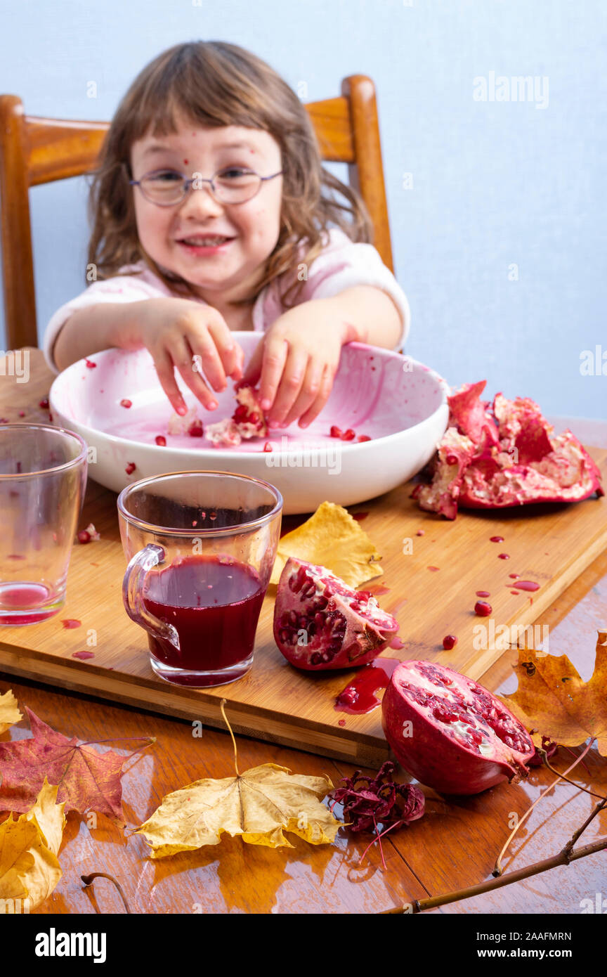 Young girl squeezing pomegranate juice, making a mess on wooden ...
