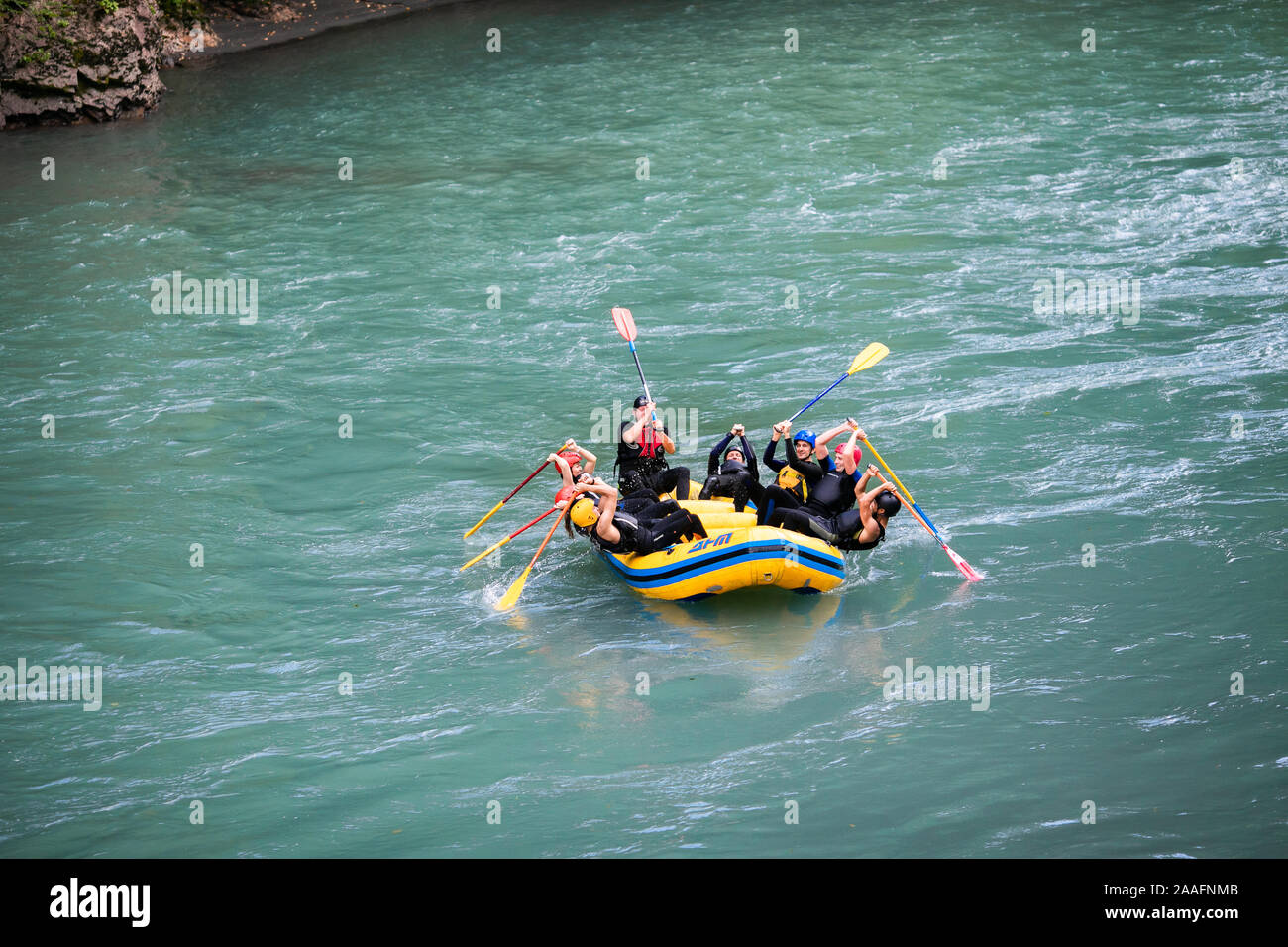 Group of happy people with guide whitewater rafting and rowing on river ...