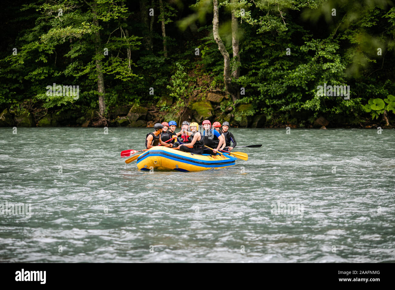 Group of happy people with guide whitewater rafting and rowing on river ...