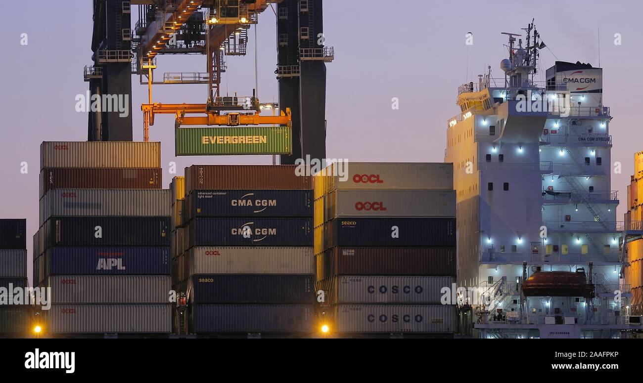 Loading containers on a ship at dawn Stock Photo - Alamy