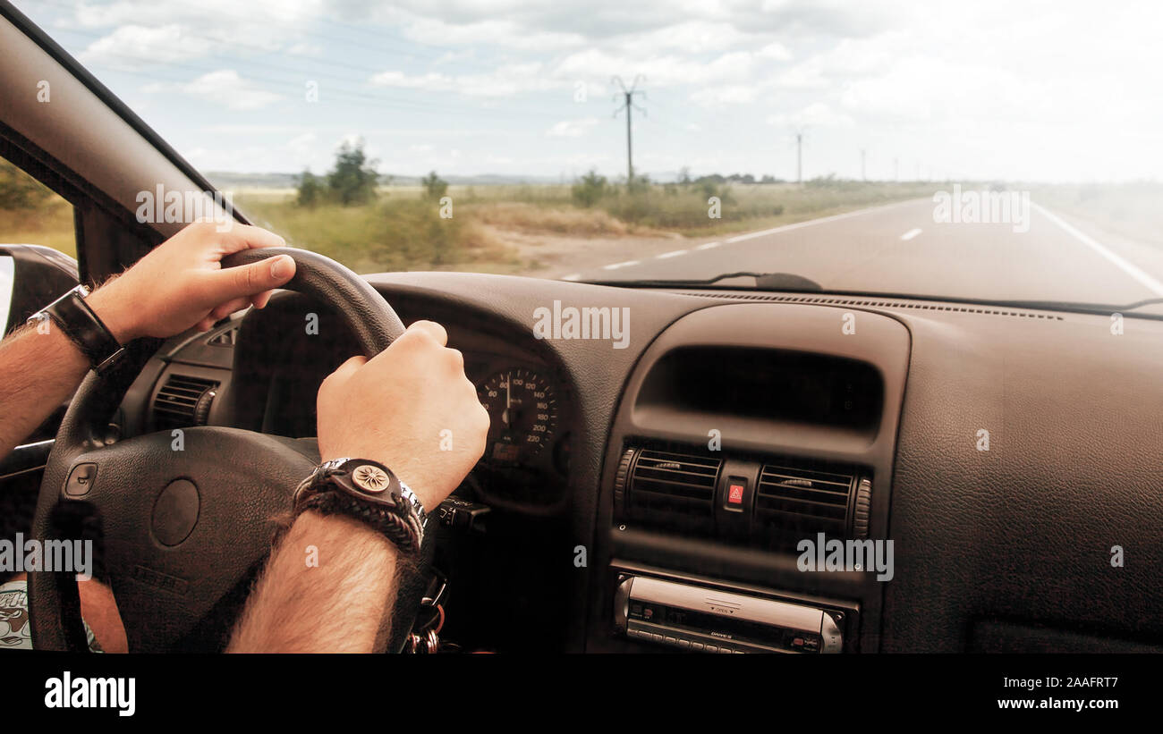 Hands driving car wheel - view from inside Stock Photo - Alamy