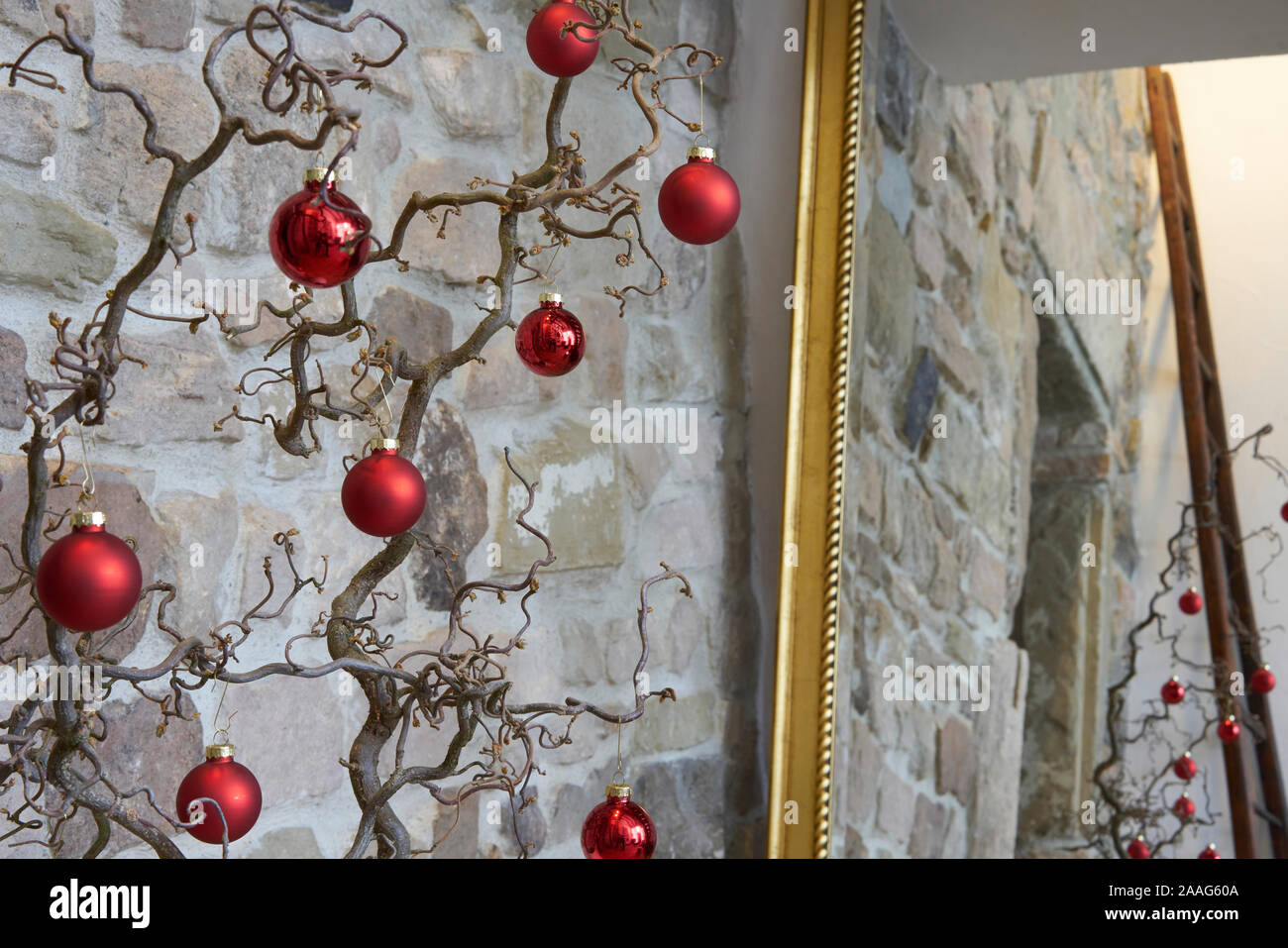 Red christmas balls at a branch in front of a stone wall, reflections ...