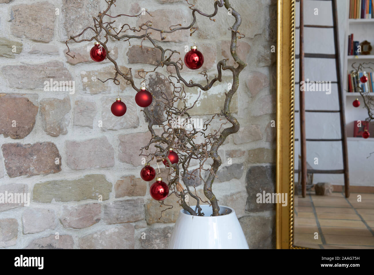 Red christmas balls at a branch in front of a stone wall in a loft ...