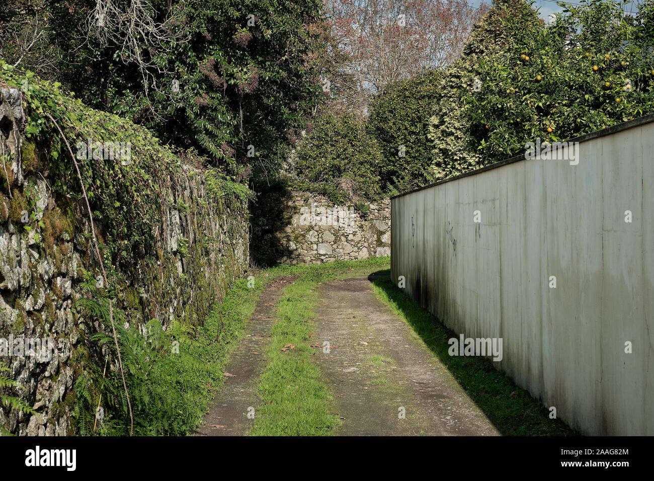 narrow way sided by one old stonewall and white concrete wall Stock ...