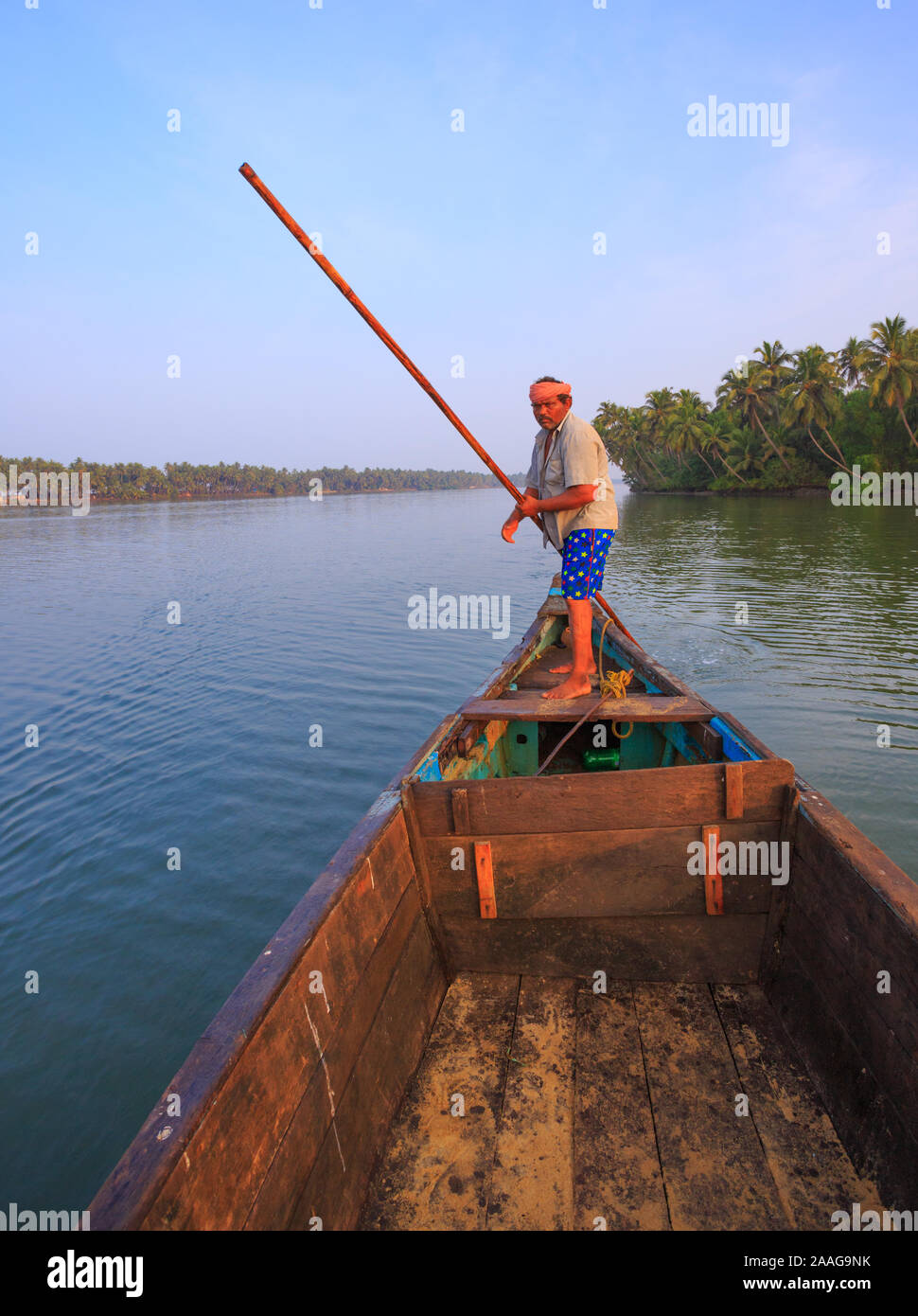 A boatman pushes his boat with a bamboo oar in the serene Suvarna river ...
