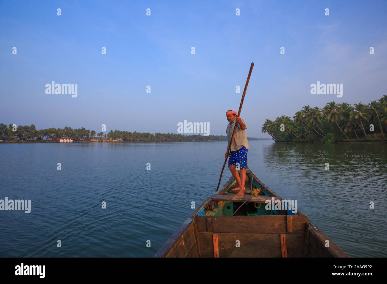 A boatman pushes his boat with a bamboo oar in the serene Suvarna river ...