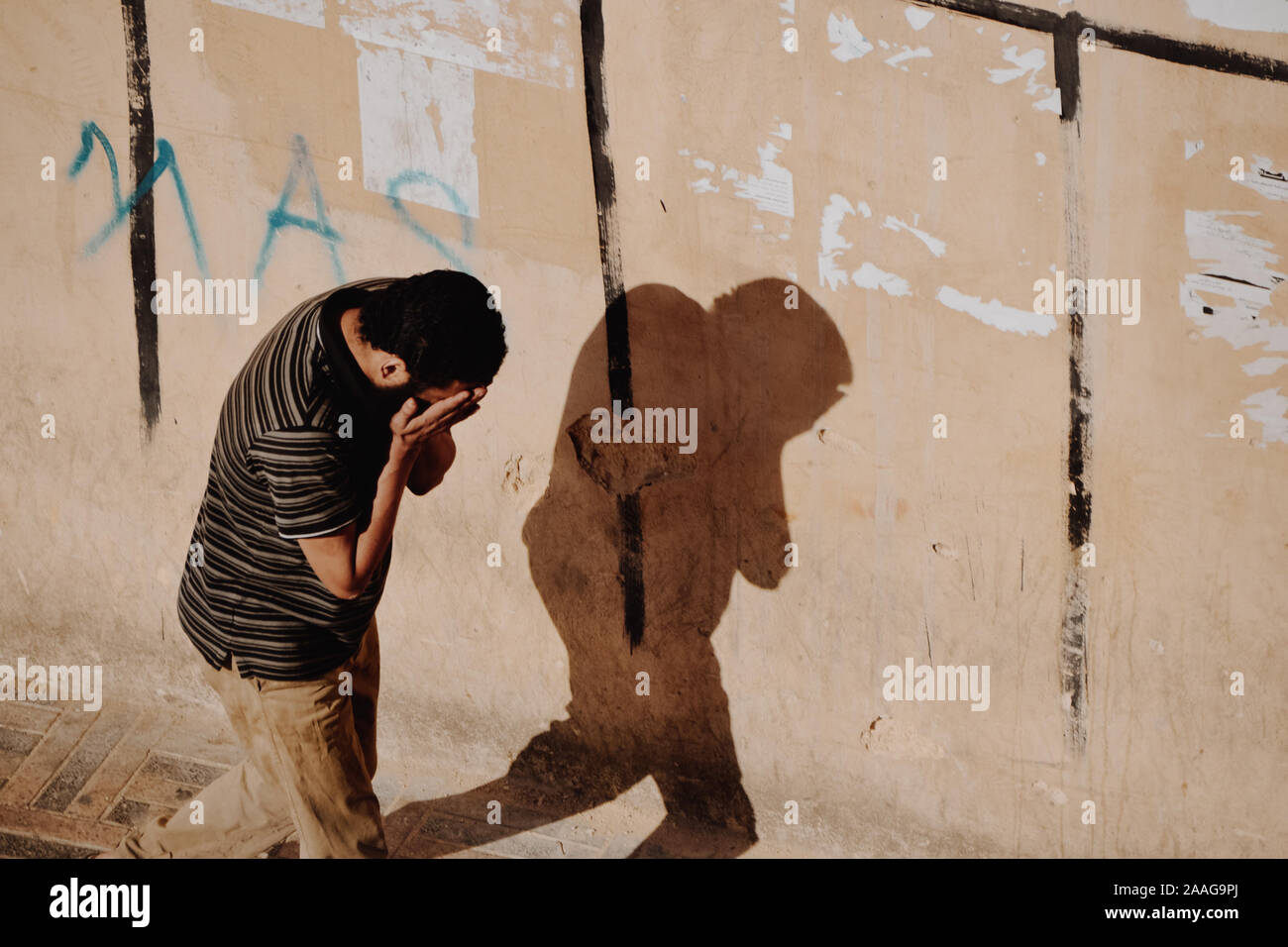 Sad man walking against a wall where his shadow can be seen Stock Photo ...