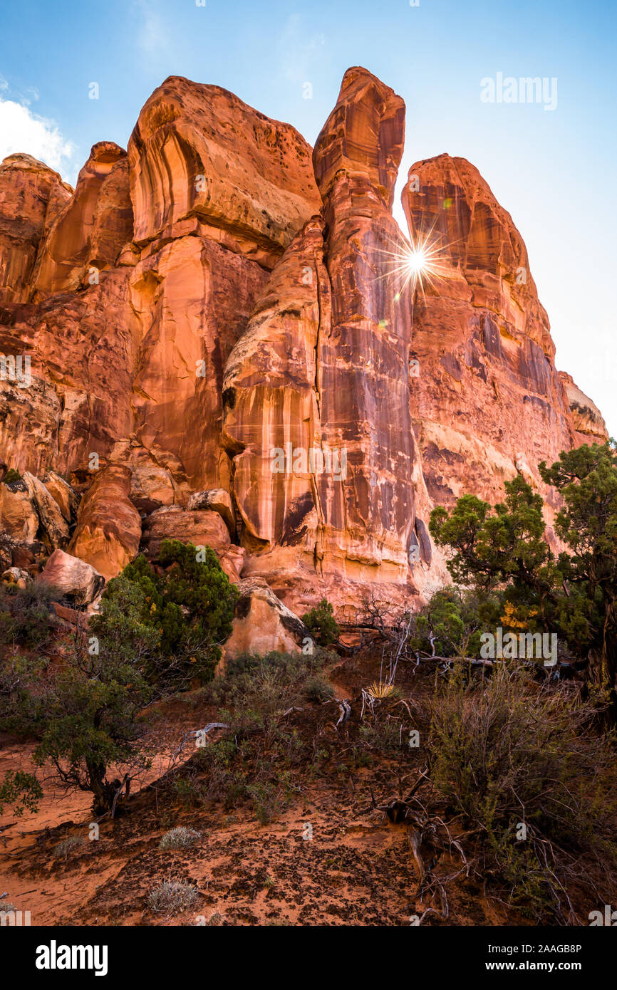 Sandstone cliff and towers with sunlight peering through narrow gap ...