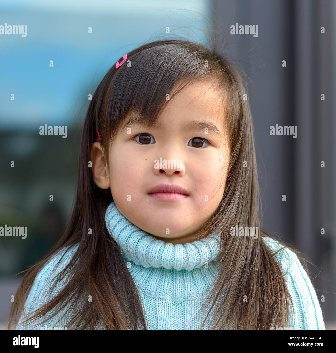 Portrait of a happy pretty little girl grinning at the camera as she ...
