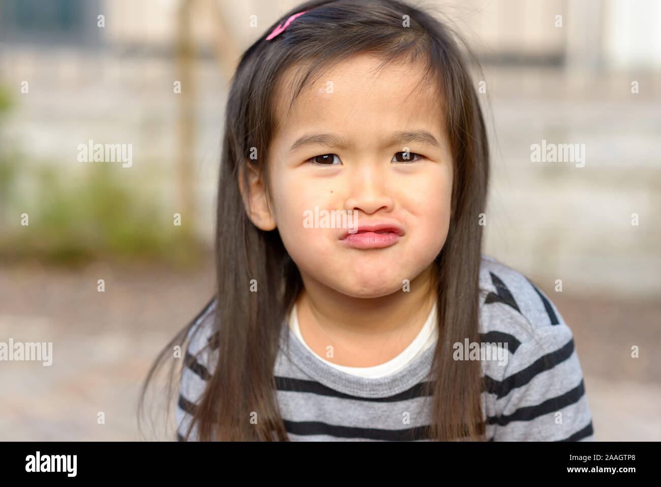 Portrait of a cute little girl pulling a funny face at the camera ...