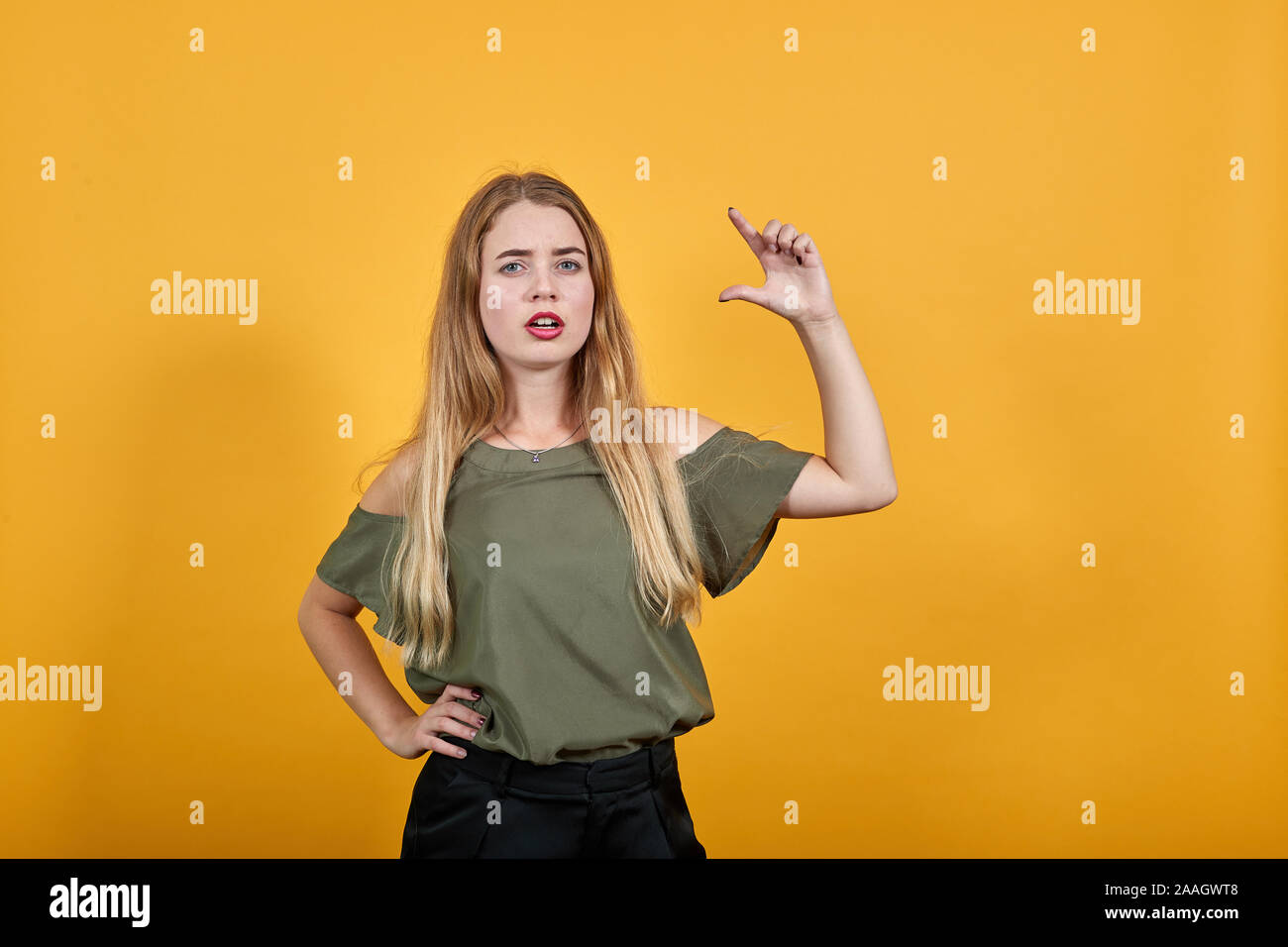 Portrait of young woman gesturing demonstrating size with workspace ...