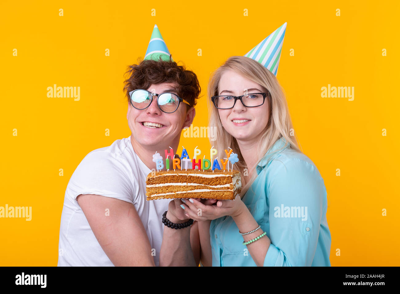 Cheerful young couple charming guy and cute girl in paper hats make ...