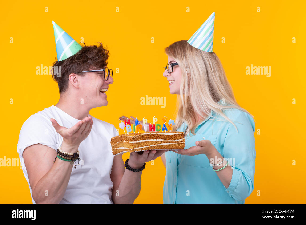 Cheerful young couple charming guy and cute girl in paper hats make ...