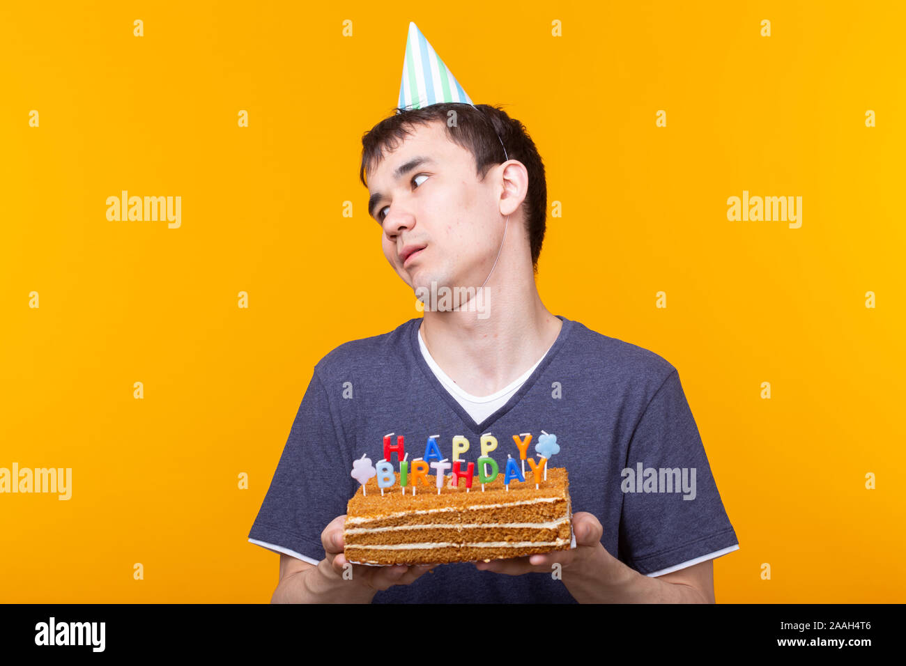 Crazy cheerful young man in glasses and paper congratulatory hats ...