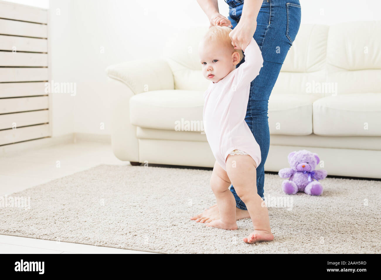 Baby taking first steps with mother's help at home Stock Photo - Alamy