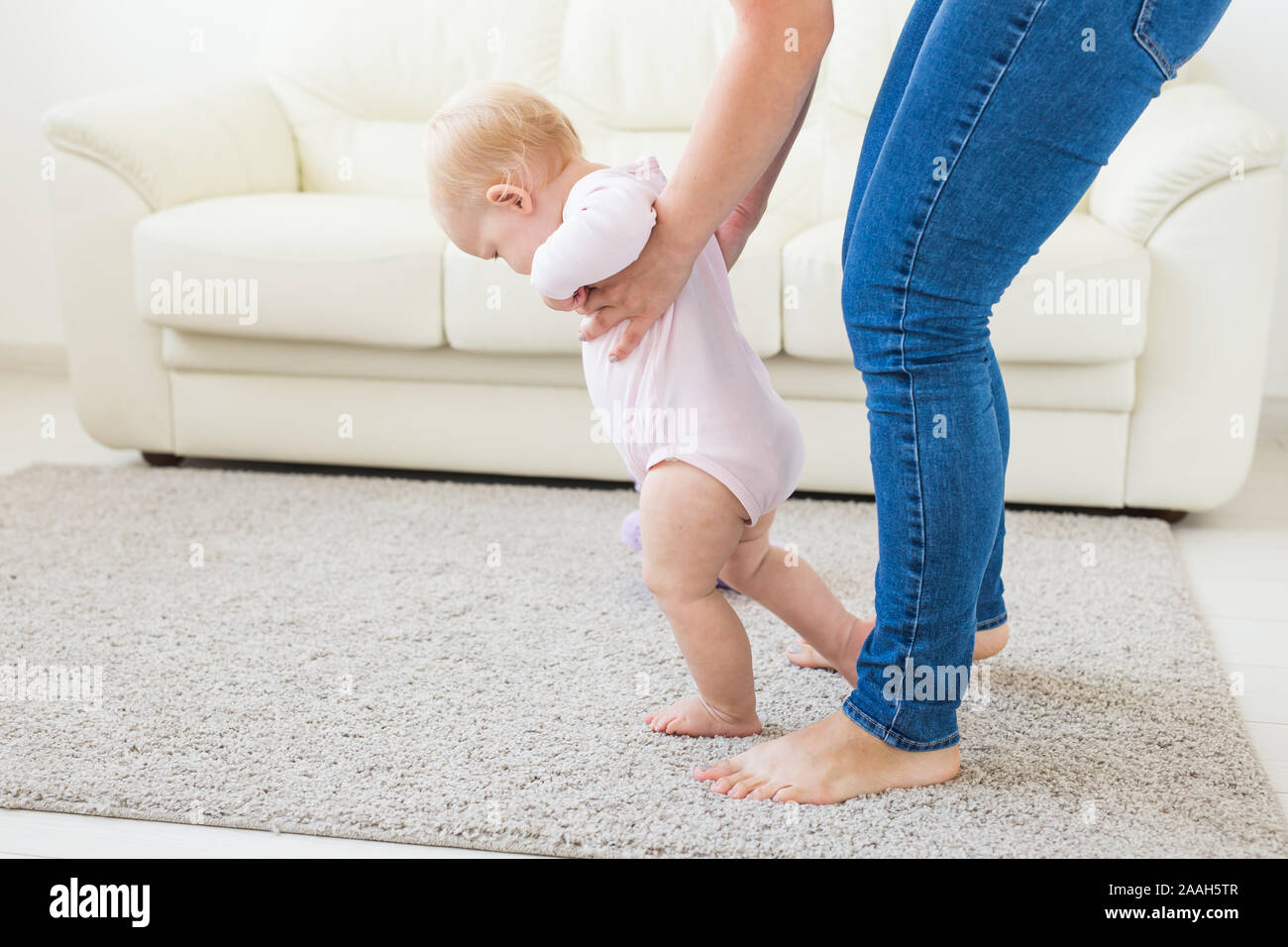 First steps of baby toddler learning to walk in white sunny living room ...