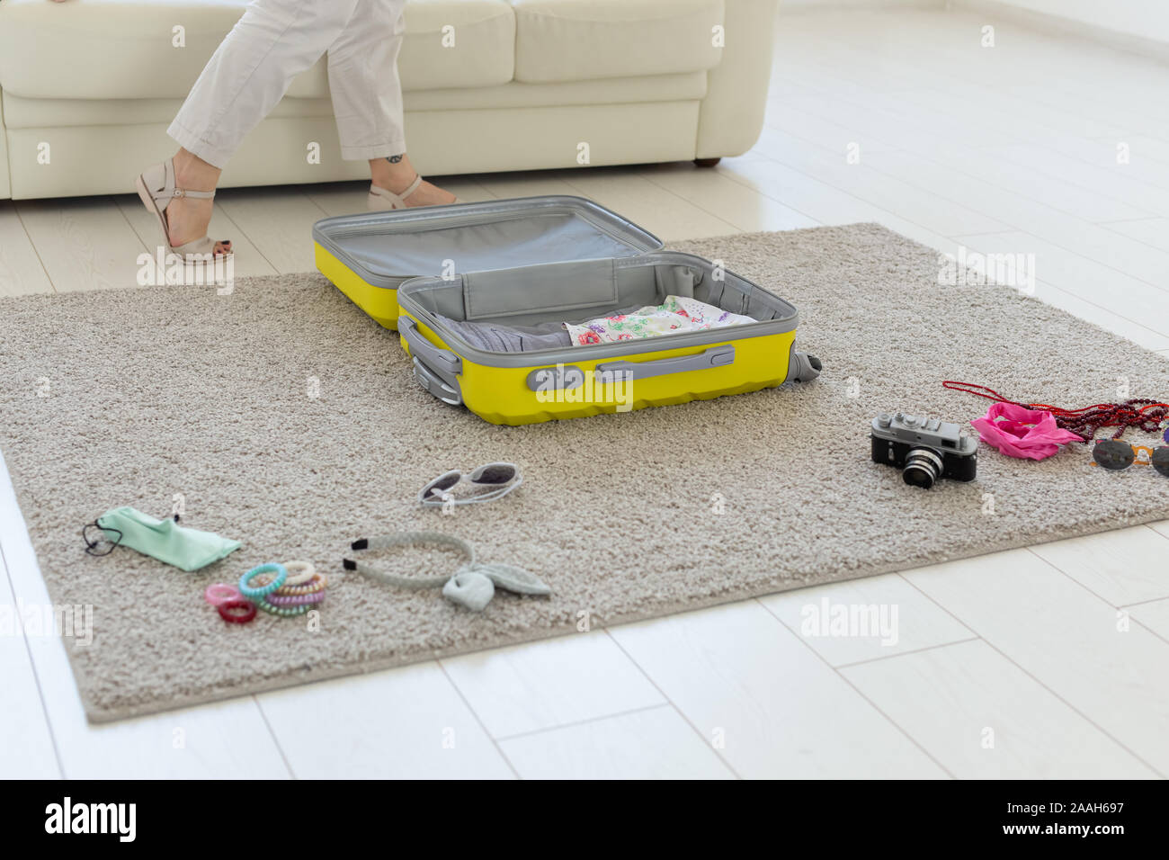 Travel, luggage and vacation concept - young woman is collecting a ...