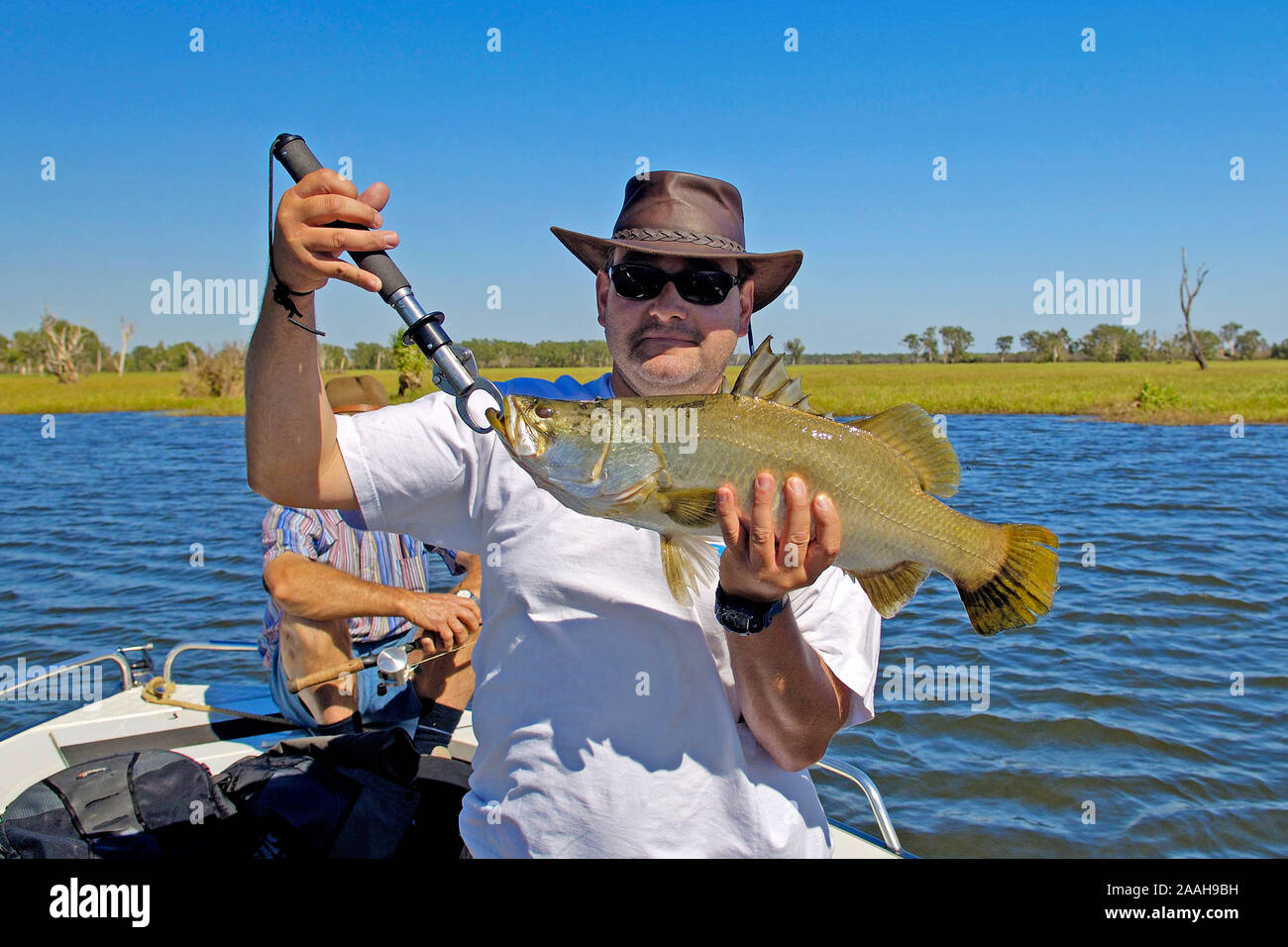 Angler praesentiert stolz seinen geangelten Barramundi Barsch, Lates ...