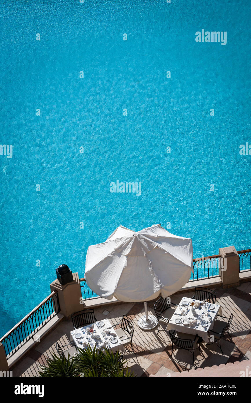 Poolside dining. Tables set for dining by the pool of a luxury hotel ...