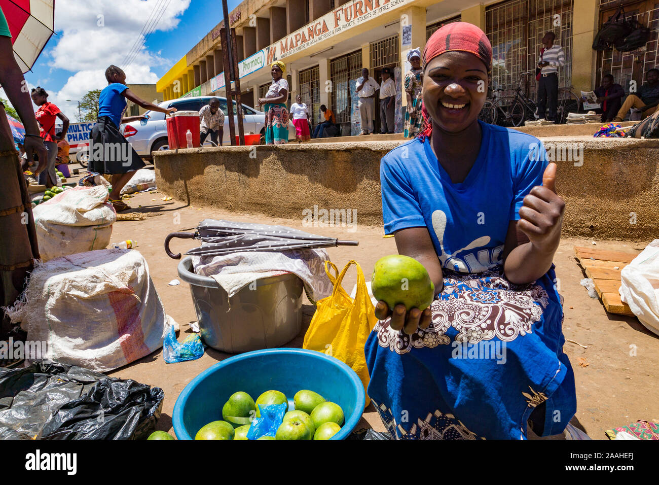 A trader selling mangoes in Mzuzu market, Malawi, gives the thumbs up ...