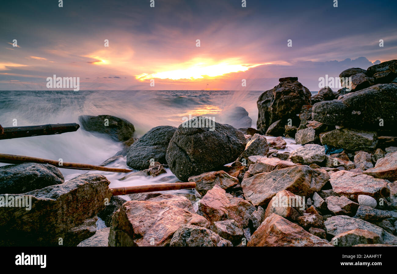 Ocean water splash on rock beach with beautiful sunset sky and clouds ...