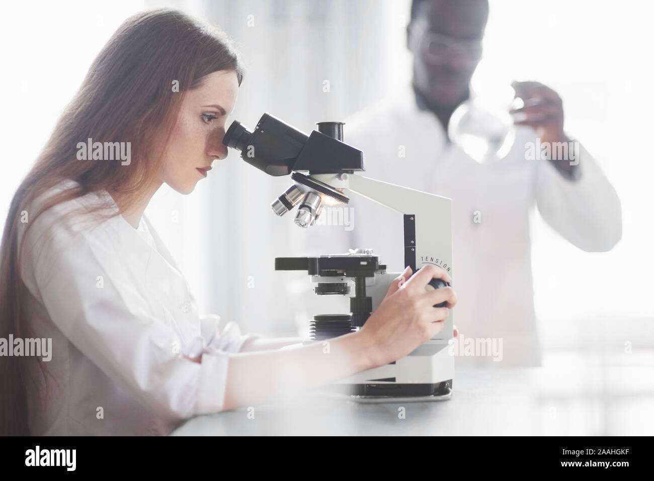 lab assistant with microscope laboratory glassware bulb with chemicals ...