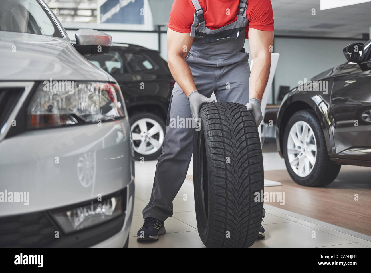 Closeup of mechanic hands pushing a black tire in the workshop Stock ...