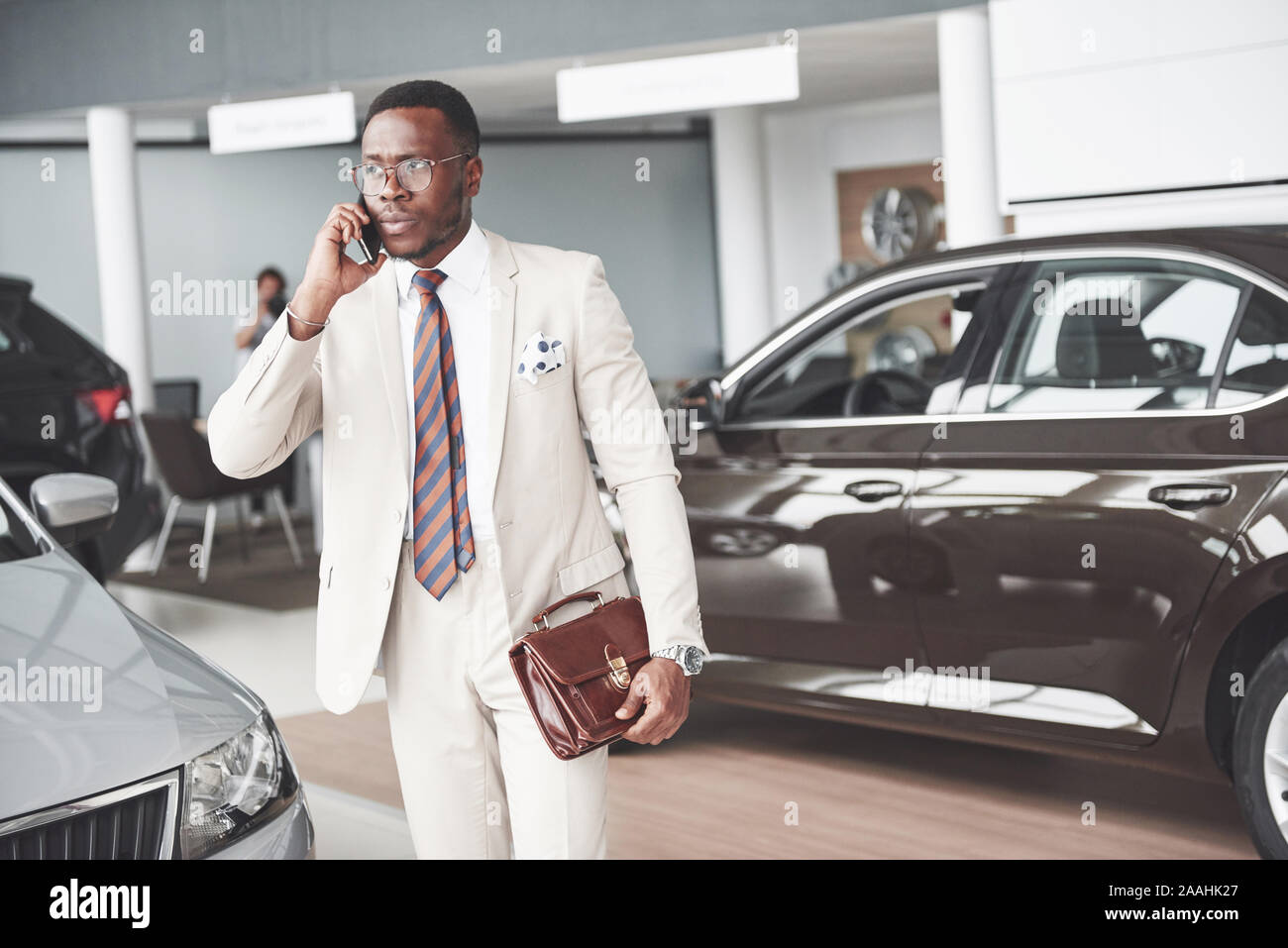 Young black businessman on auto salon background. Car sale and rent ...