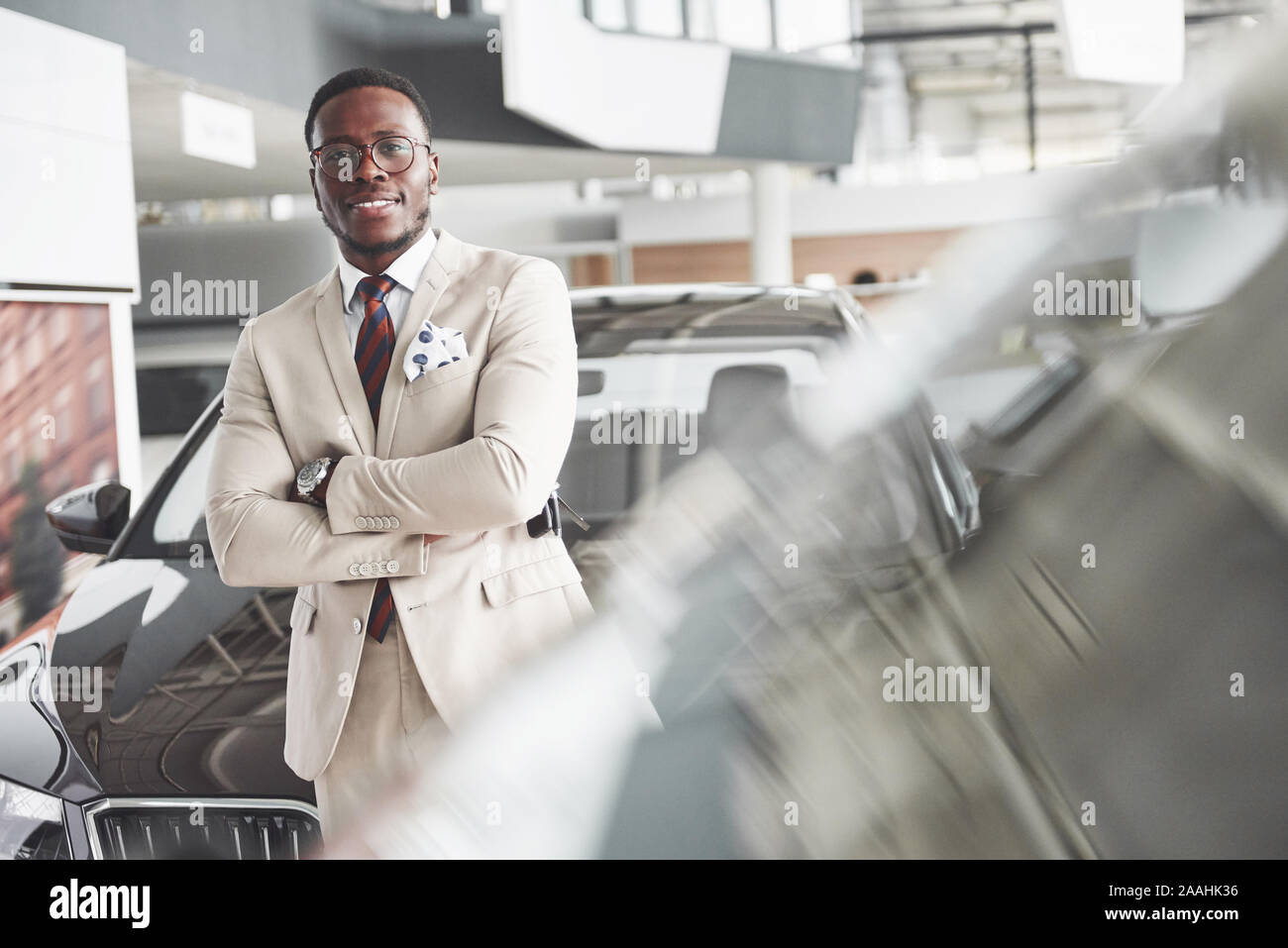 Young black businessman on auto salon background. Car sale and rent ...