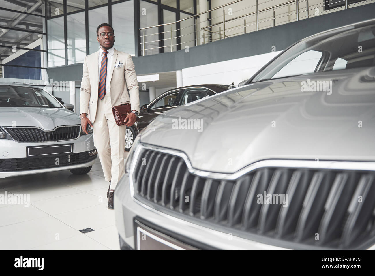 Young black businessman on auto salon background. Car sale and rent ...