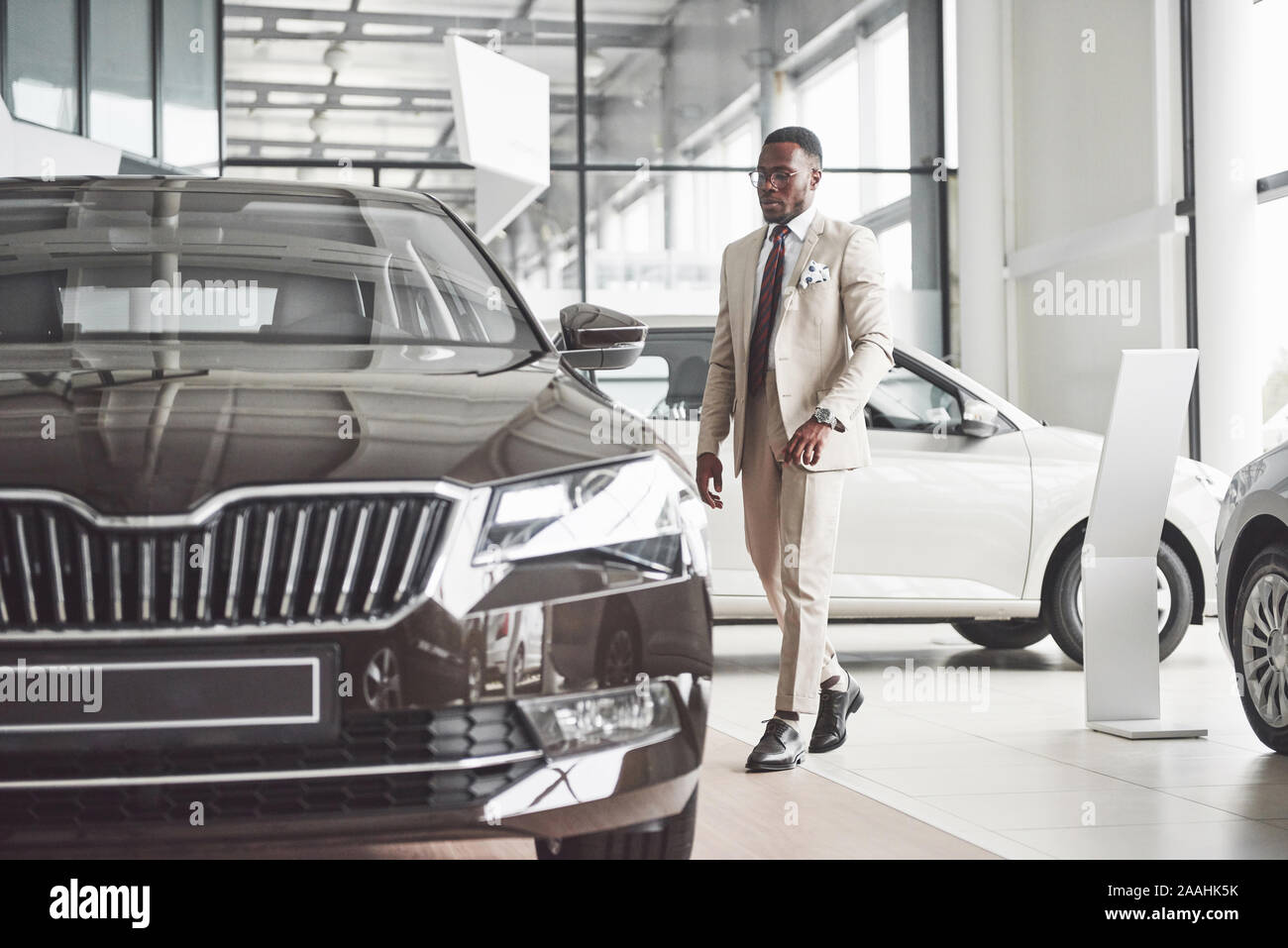 Young black businessman on auto salon background. Car sale and rent ...