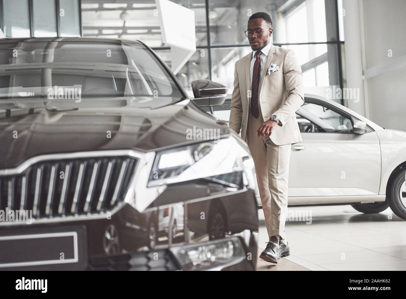 Young black businessman on auto salon background. Car sale and rent ...