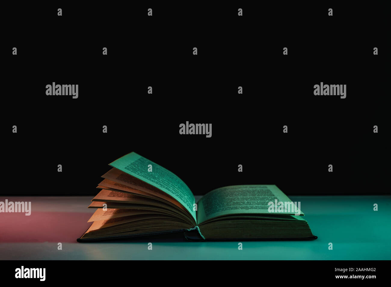 Beautiful open book in the color light on a table and night background ...