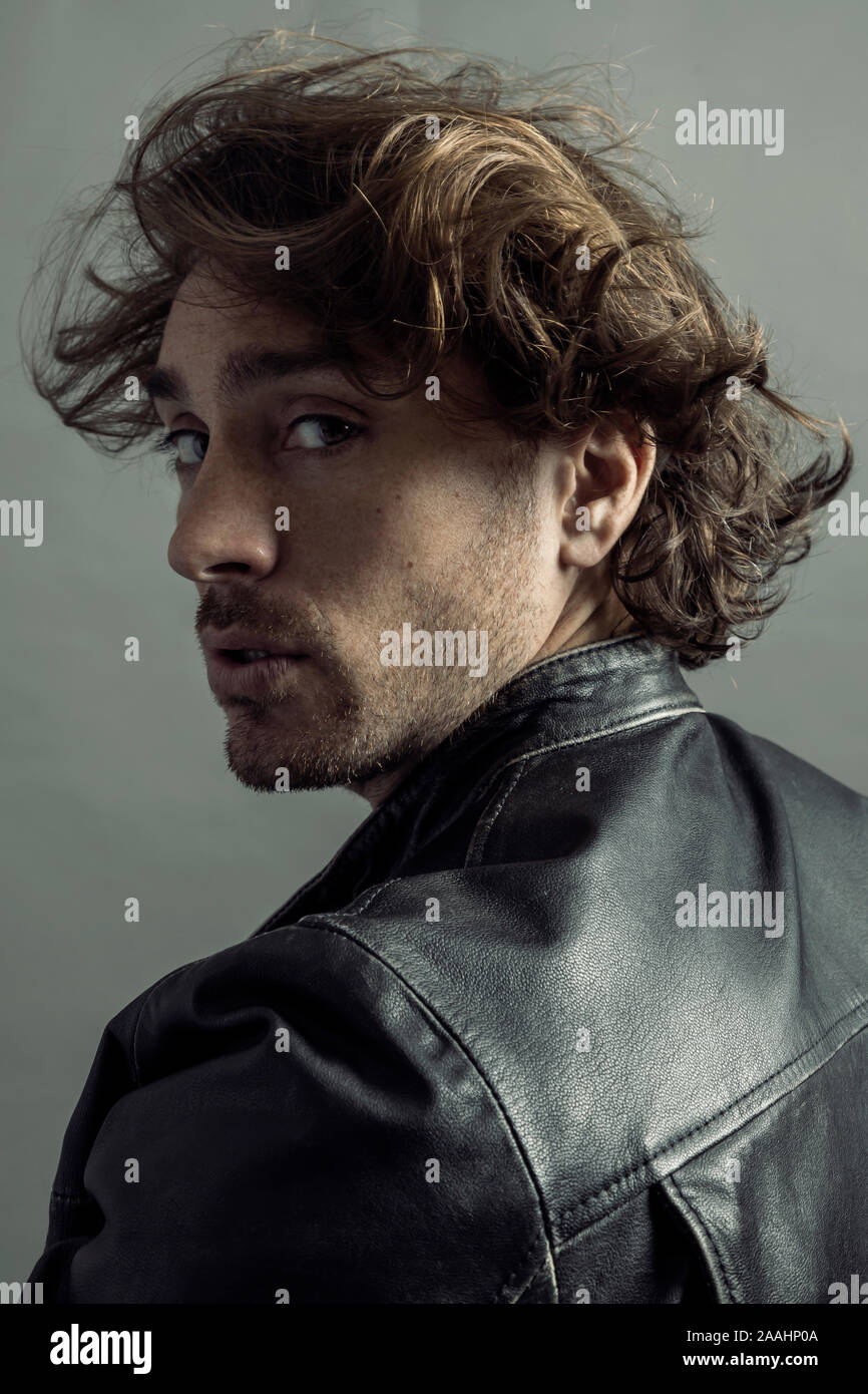 Man in leather jacket turning around surprised, grey background Stock ...