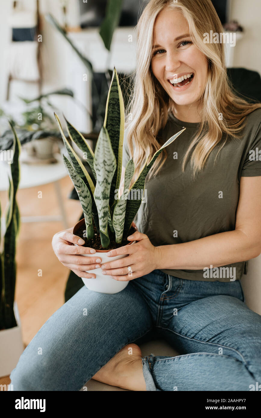 Woman carrying pot of house plant on lap Stock Photo - Alamy