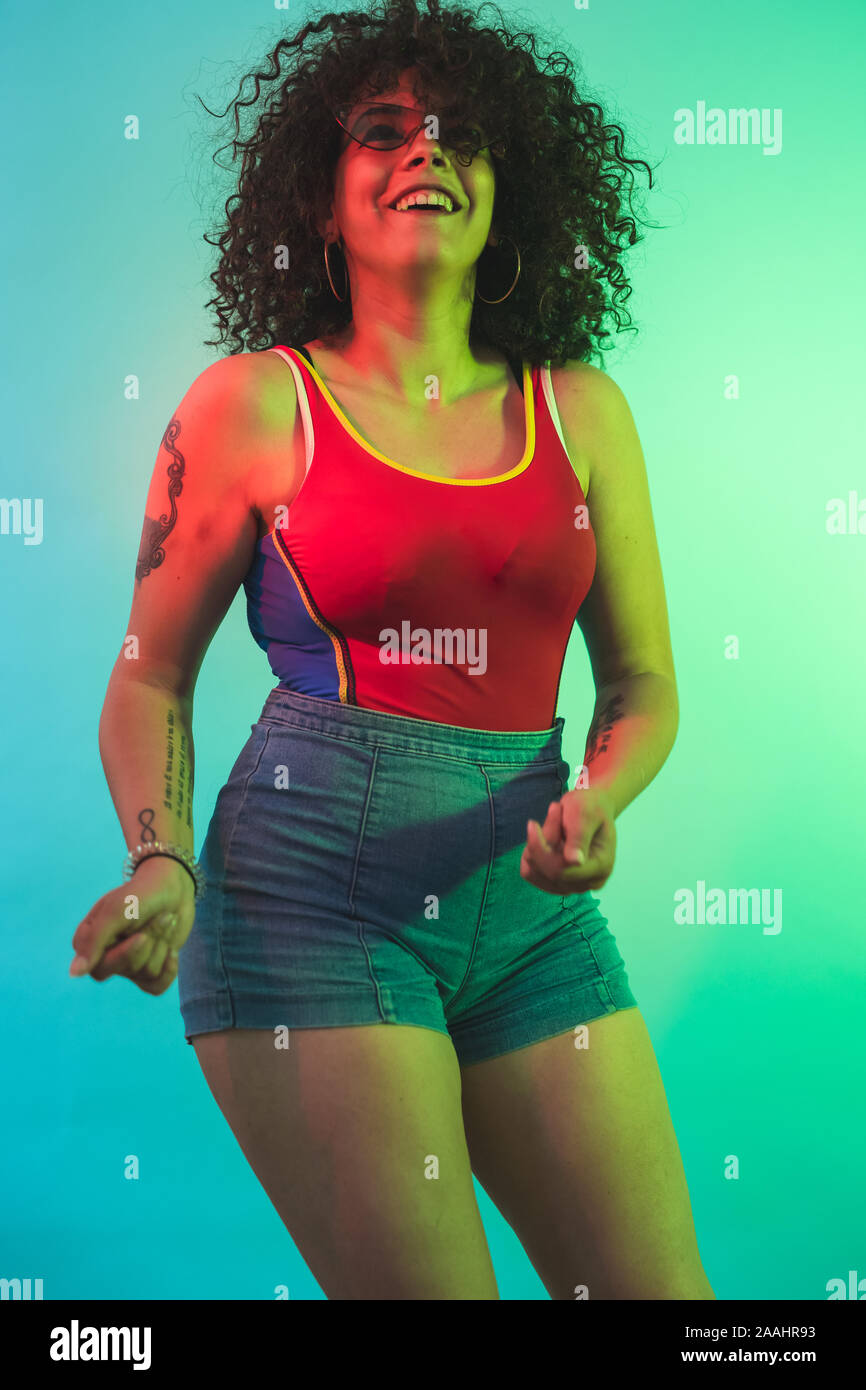 Young woman in red tank top dancing against turquoise background Stock ...