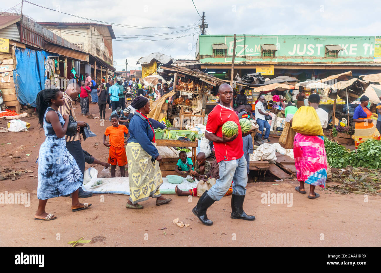 Local African man carrying a pair of large melons at a busy roadside ...