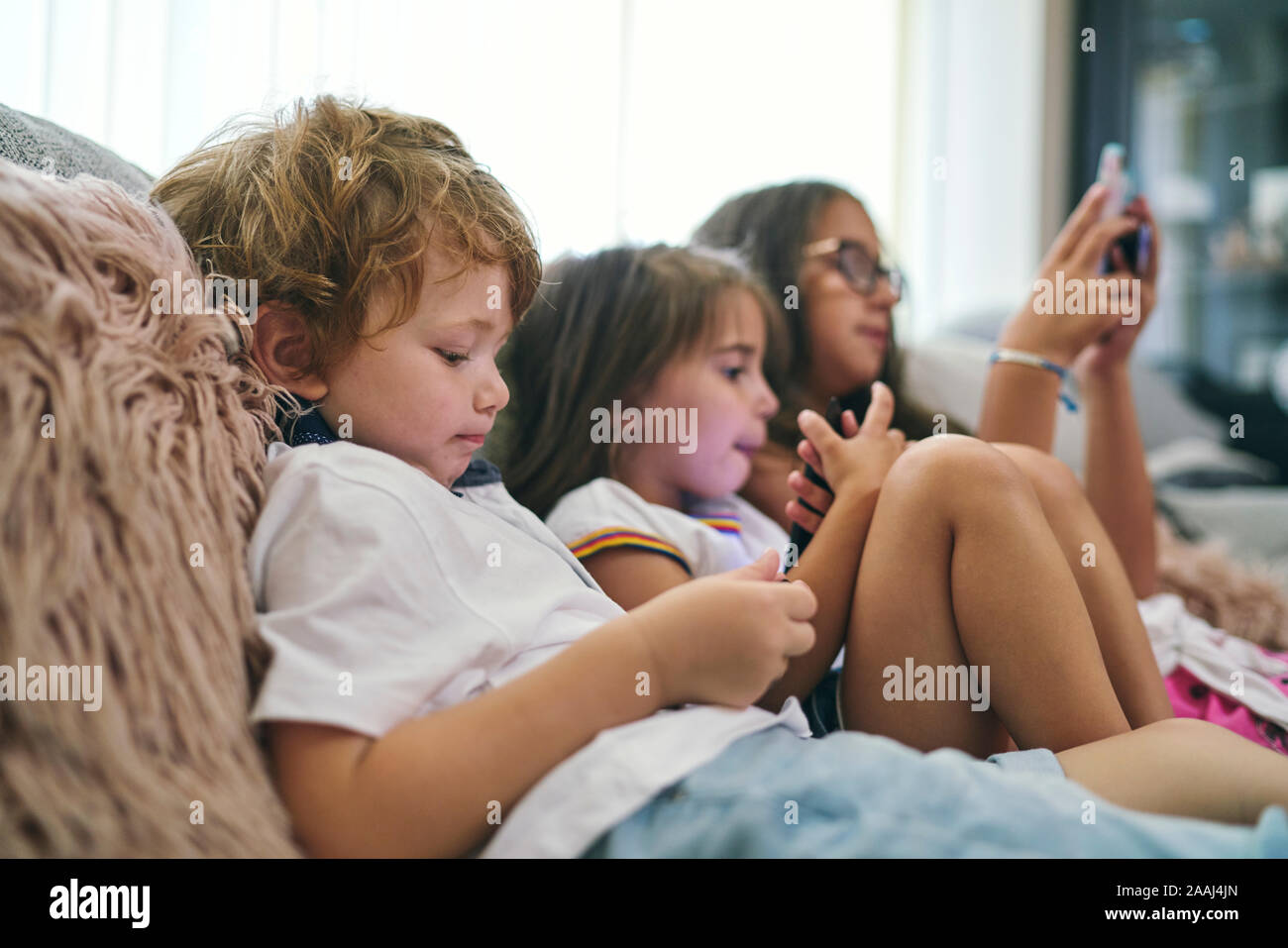 Friends enjoying computer games on sofa Stock Photo - Alamy
