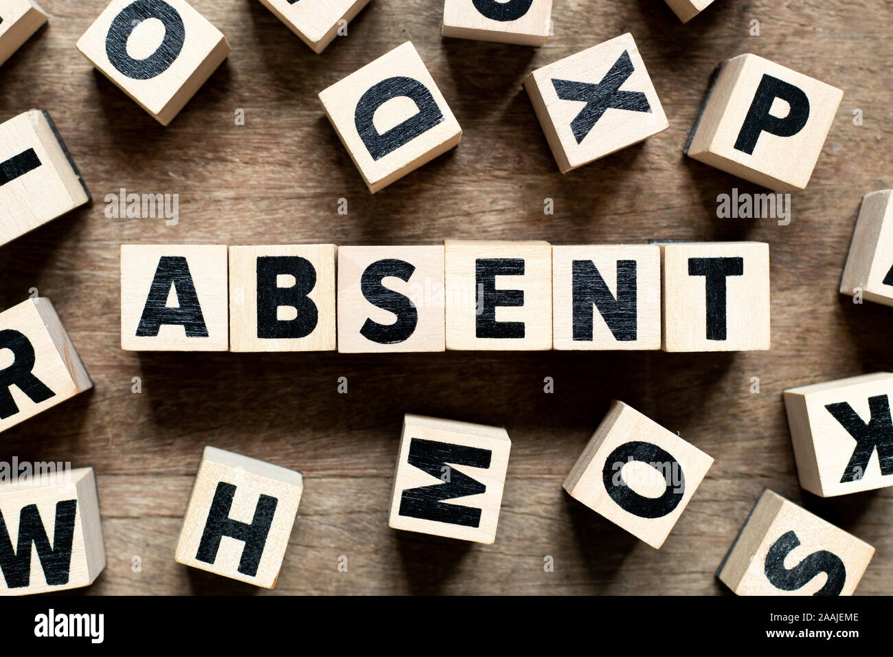Letter block with word absent on wood background with another alphabet ...